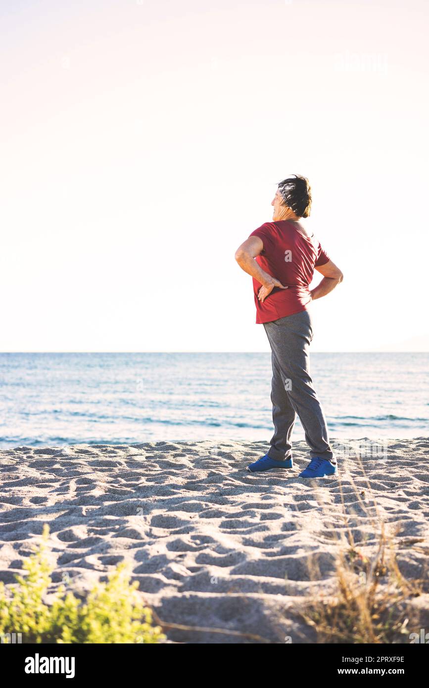 Senior woman doing exercise at the beach. Standing hands on hips ...