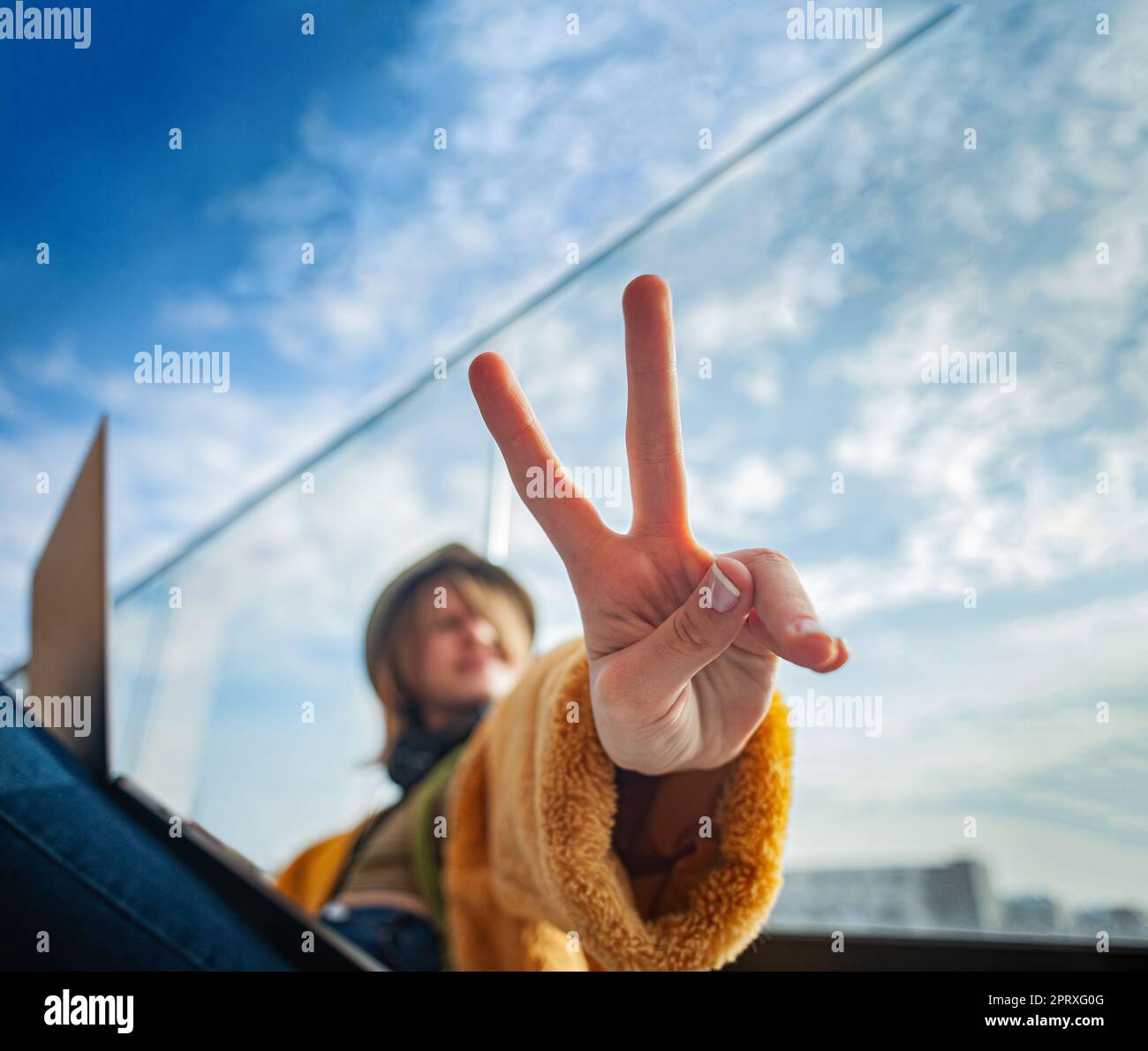 Teenage girl, social media influencer, showing peace sign, sitting on ...