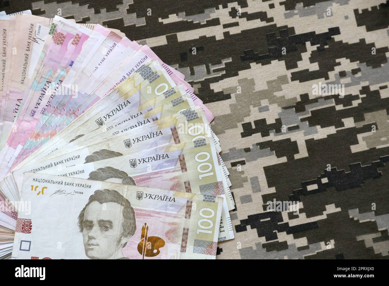 Ukrainian hryvnya bills on fabric with texture of Ukrainian military ...