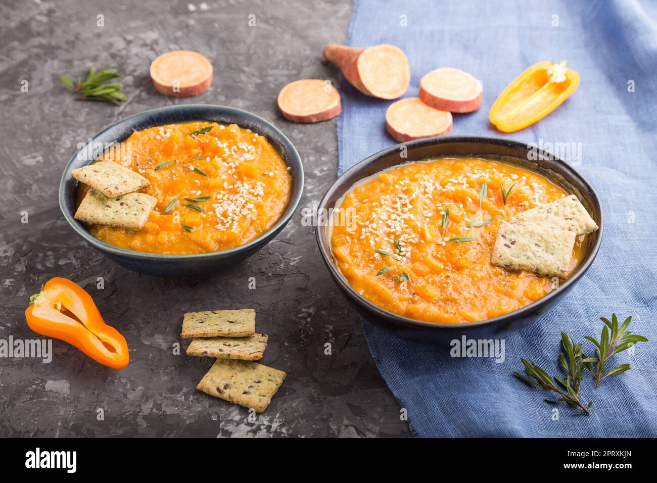 Sweet potato or batata cream soup with sesame seeds and snacks in blue ...