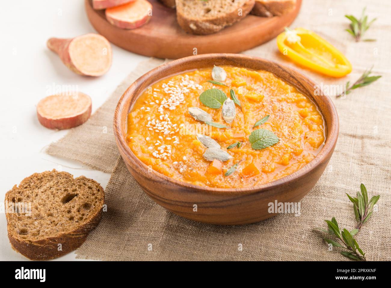 Sweet potato or batata cream soup with sesame seeds in a wooden bowl on ...