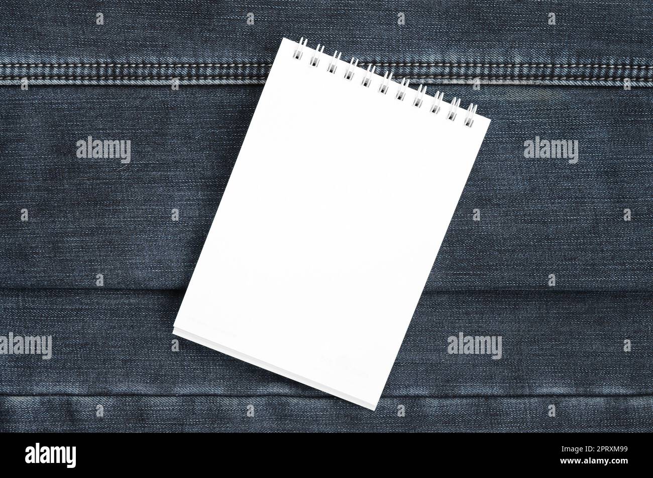 White notebook with clean pages lying on dark blue jeans background ...