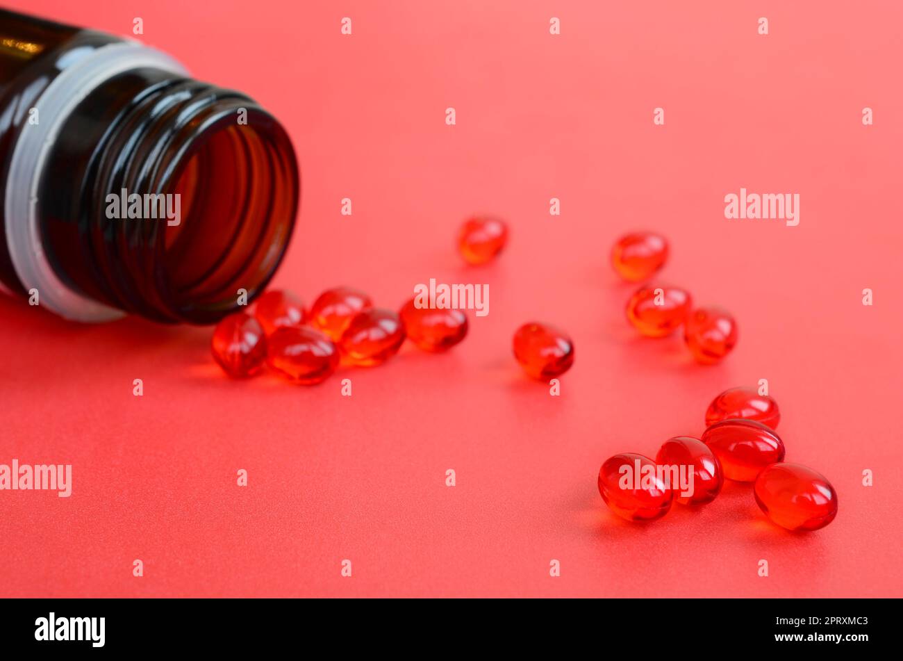 A lot of transparent red tablets were scattered from a small glass ...