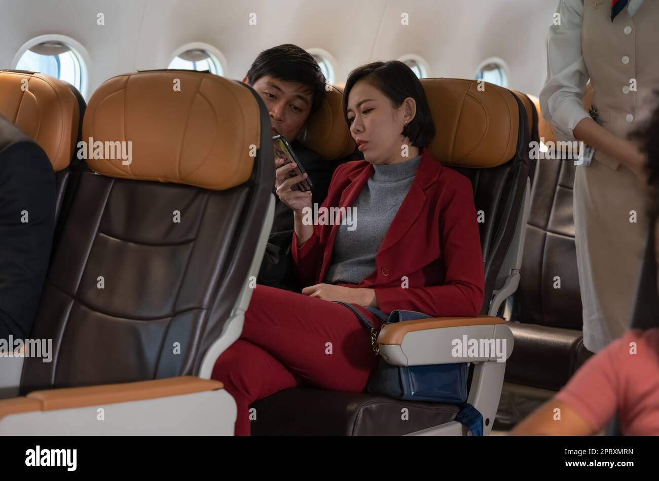 Couple passengers sitting on seat and using mobile phone in airplane ...