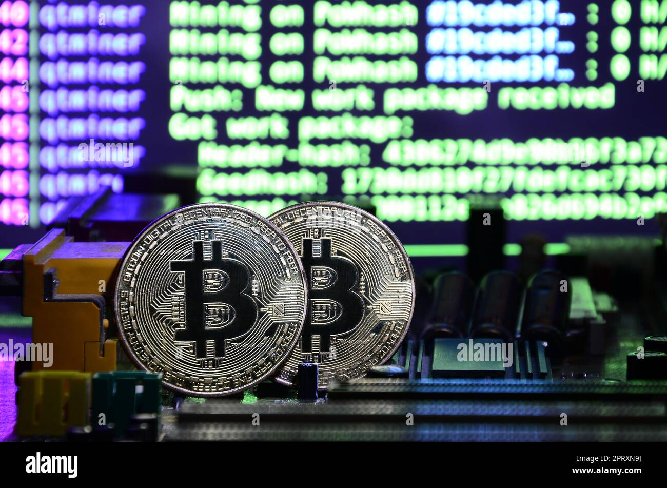 Two bitcoins lies on a videocard surface with background of screen ...