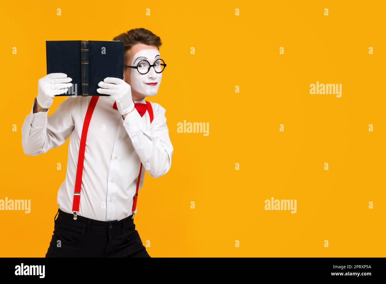 portrait of mime man artist reading book isolated on yellow background ...