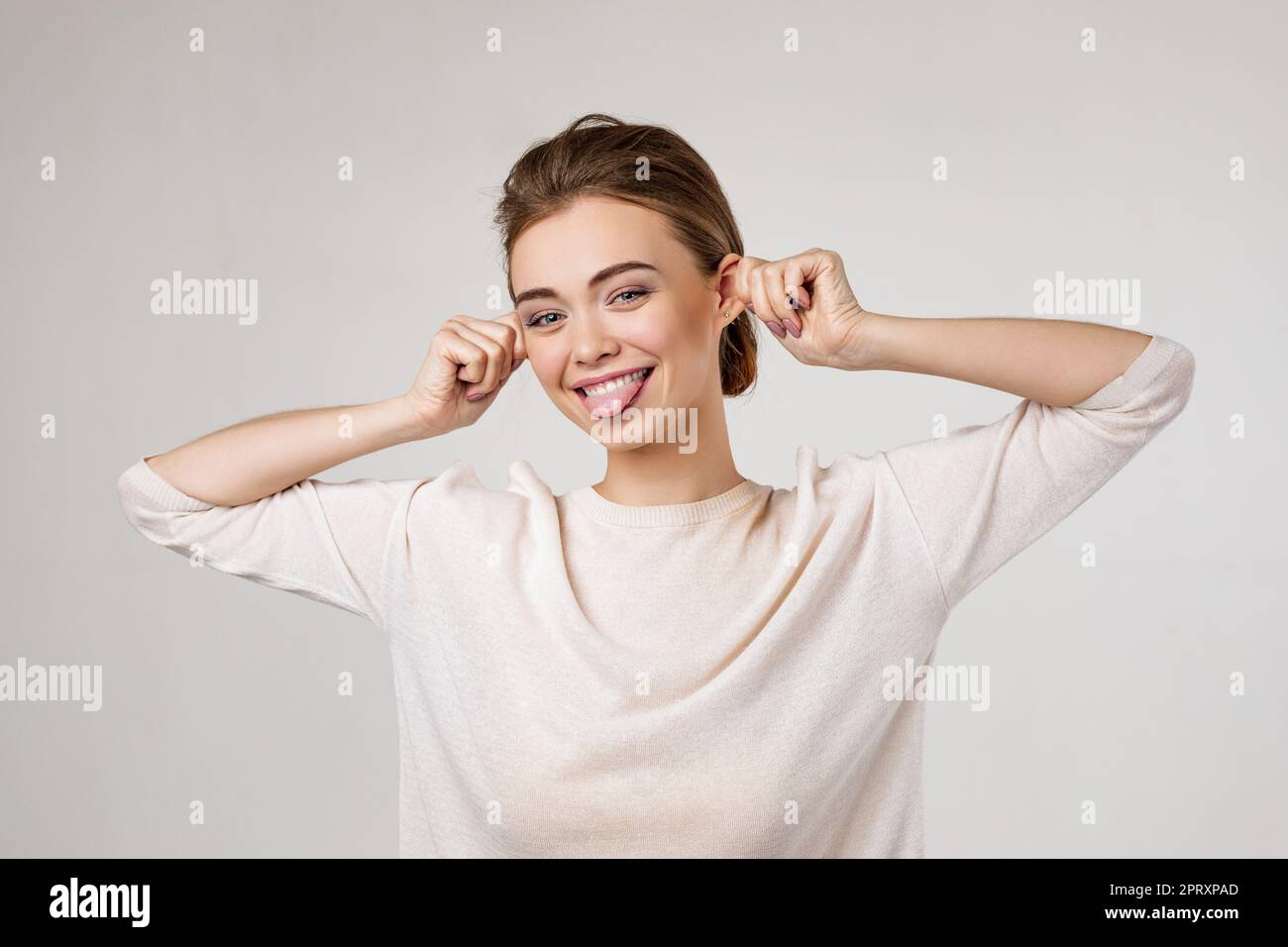 Cute young woman having fun and fooling around over gray background ...