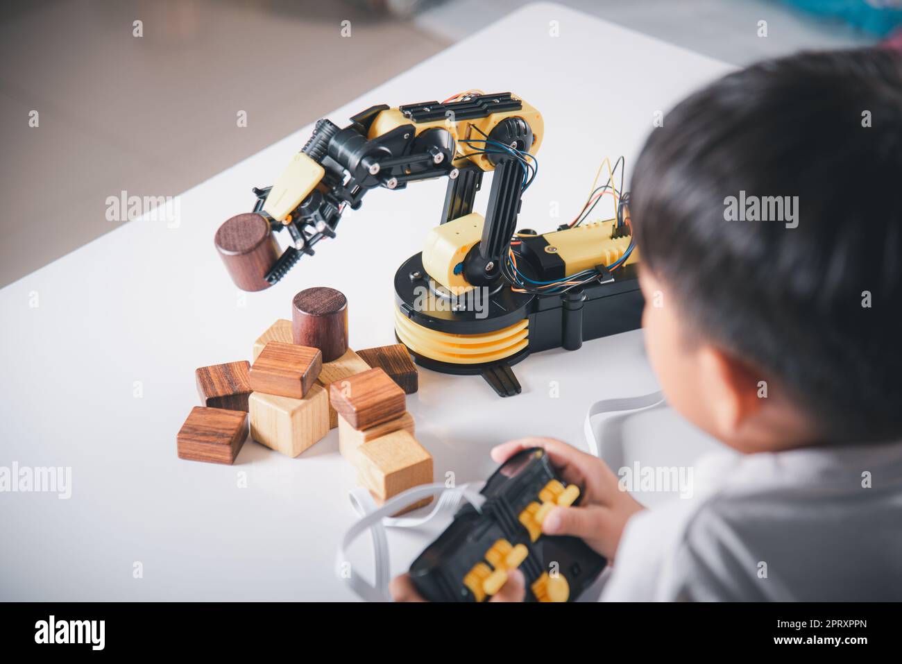 Happy Asian little boy using remote control playing robotic machine arm ...