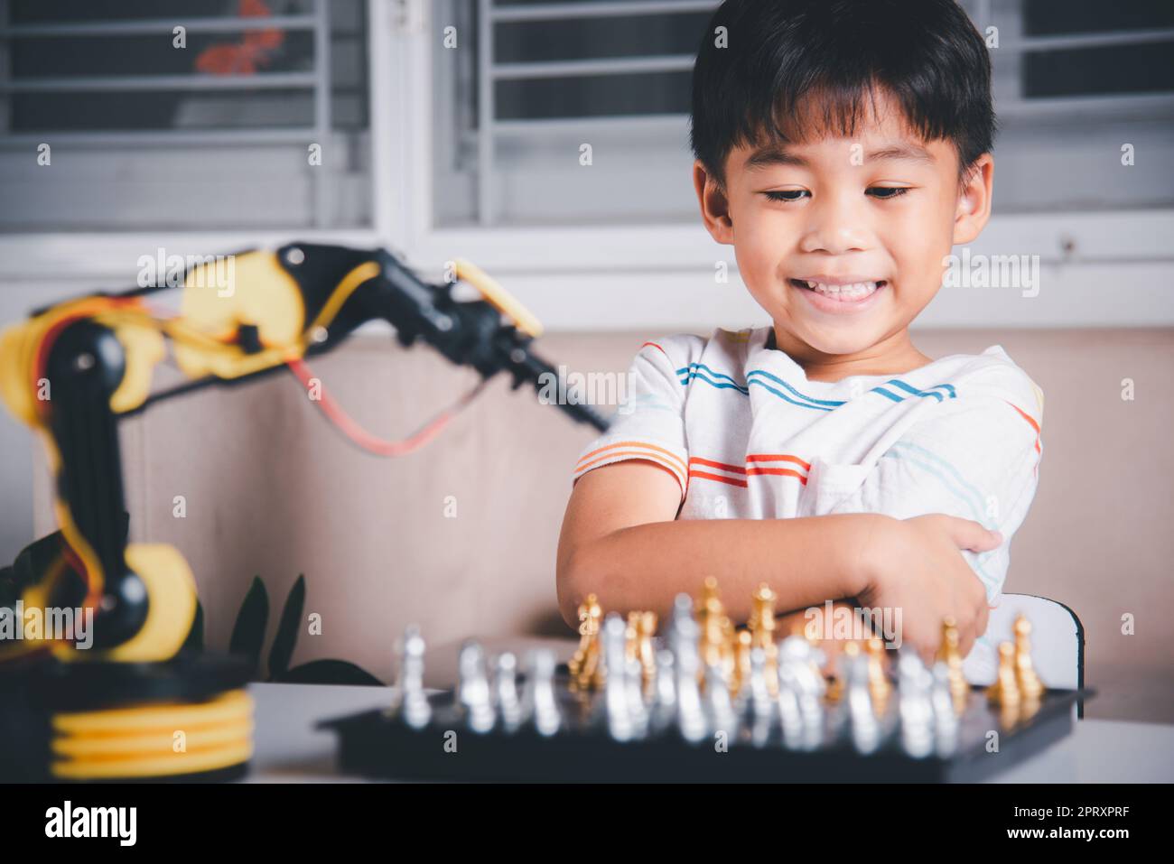 Asian little boy is playing chess with robot machine arm, STEM ...