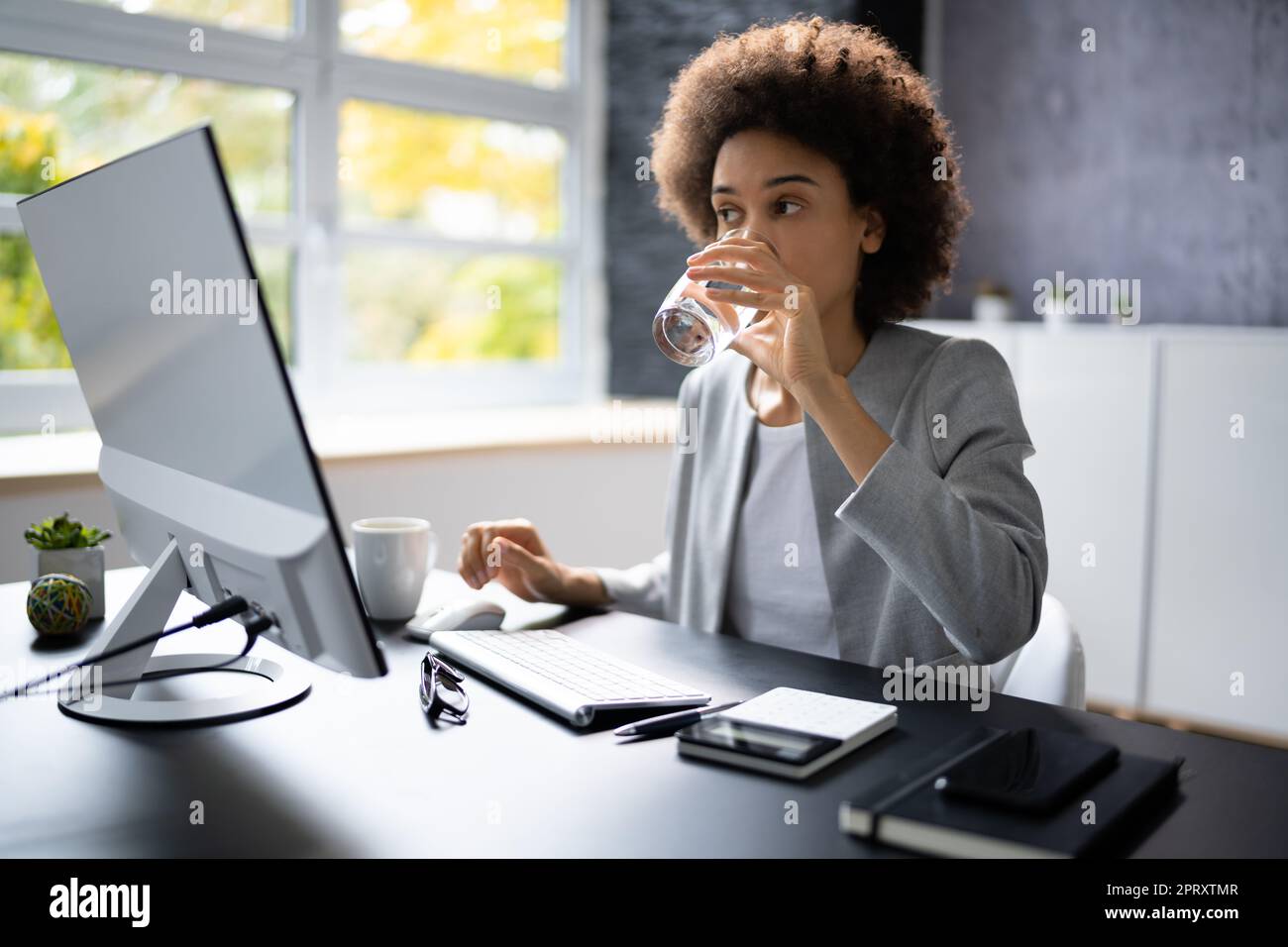 Water Bottle On Desk And Woman In Foreground Using Computer Stock Photo ...