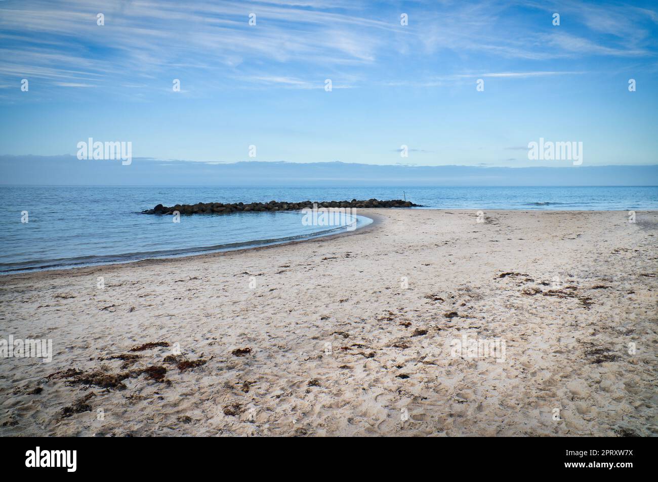 Sandy beach on the coast of Denmark. Stone groyne in the bay, sunshine ...