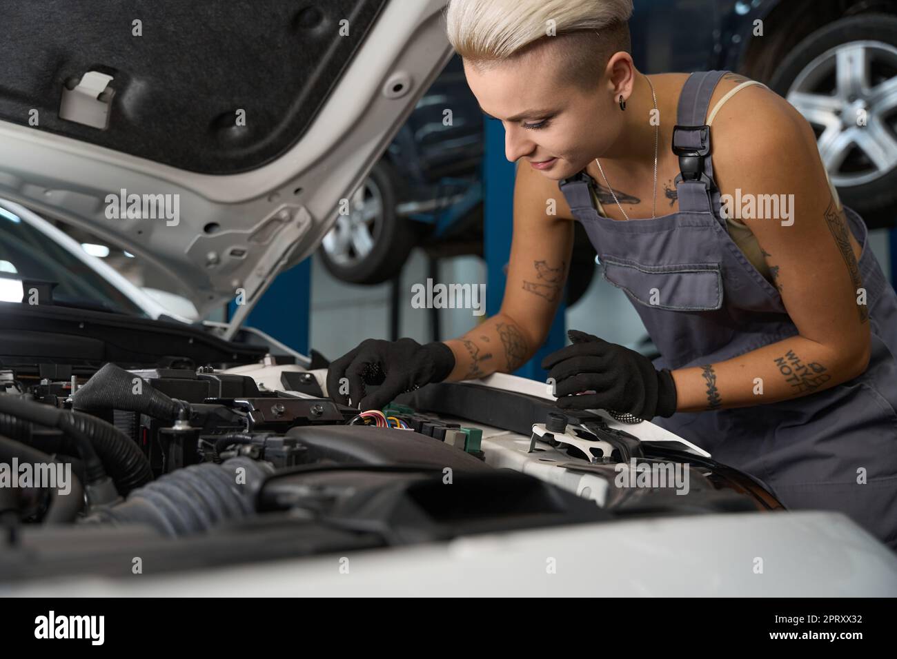 Young woman in work overalls repairs a car engine Stock Photo - Alamy