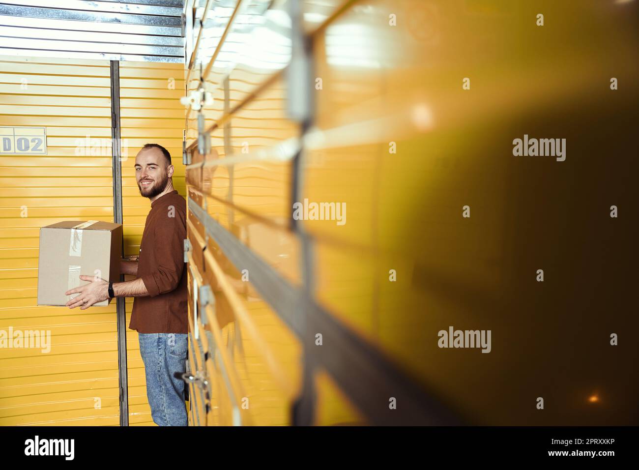 Side view of smiling young man standing with cardboard box Stock Photo ...