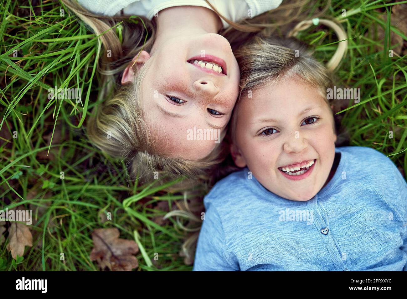 Cheerful childhood days. Portrait of two little sisters lying on the grass outside Stock Photo ...