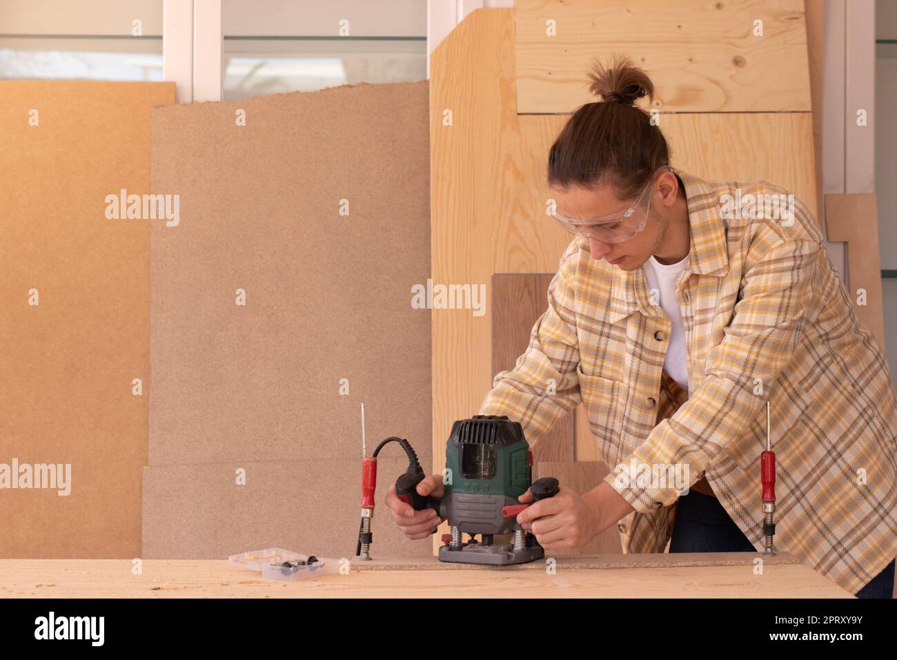Young male carpenter using milling machine while working with wood in ...
