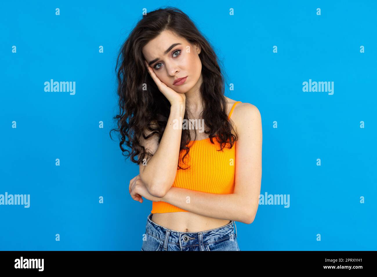 Portrait of depressed dramatic woman with wavy hair in white jacket ...