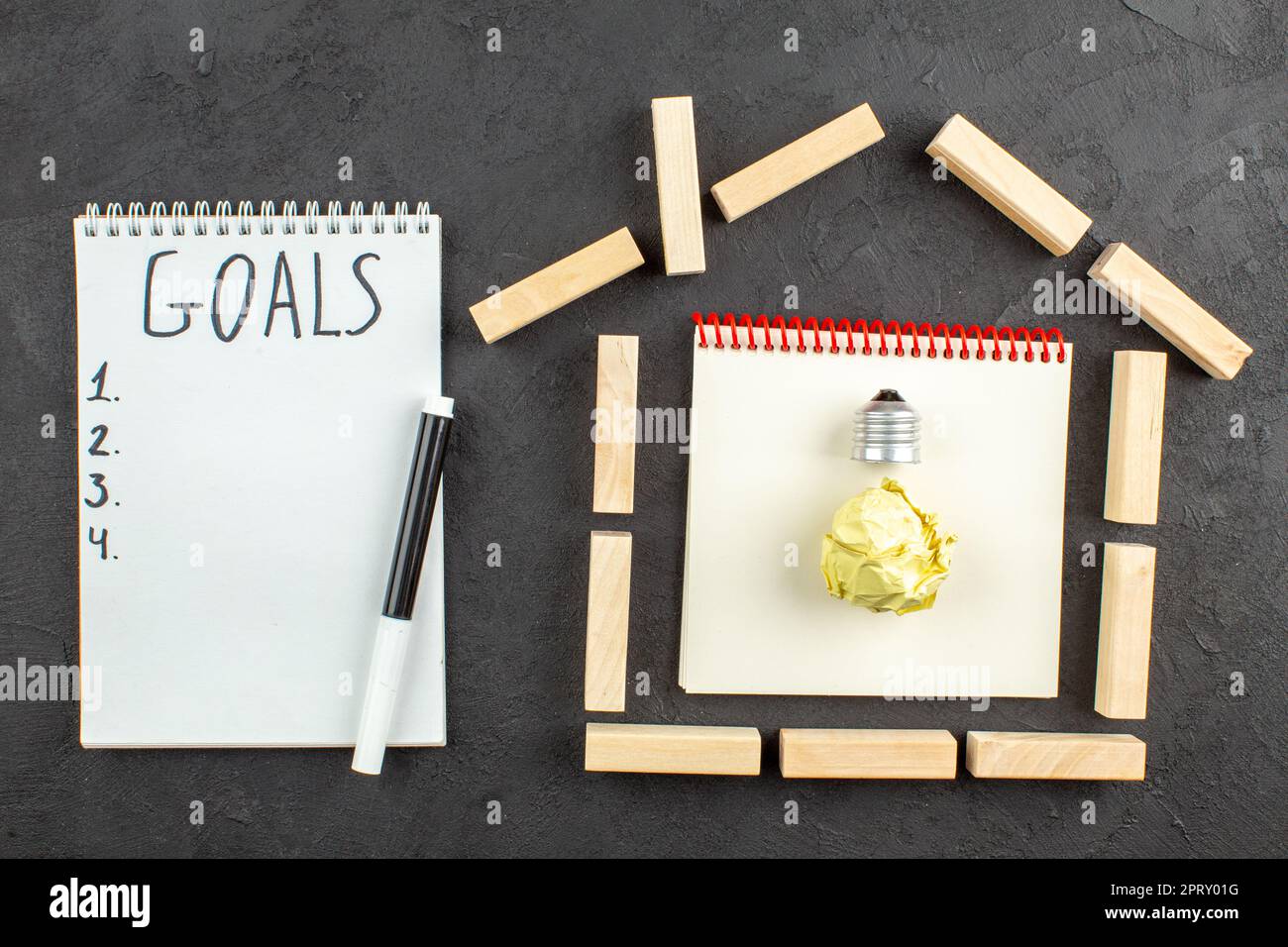 top view house shaped wood blocks goals written on notepad black marker ...