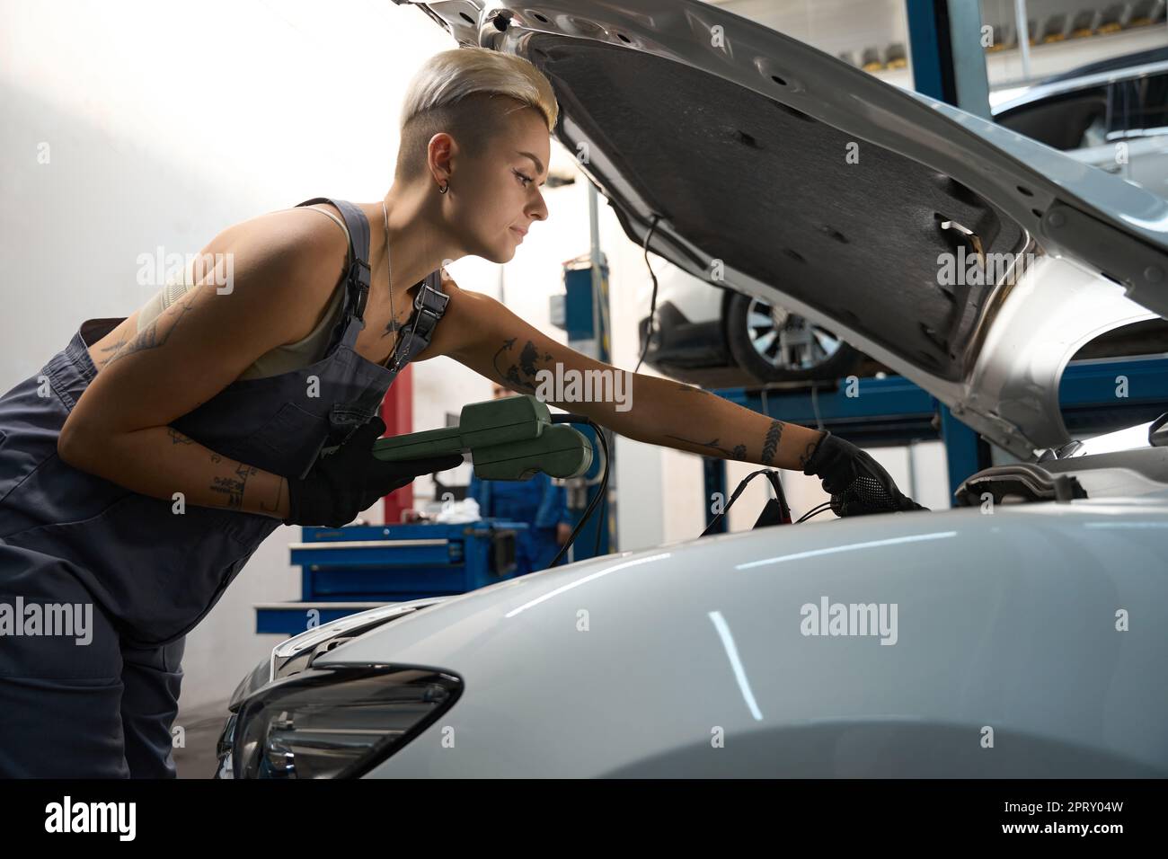 Car mechanic works under hood of car with special scanner Stock Photo ...
