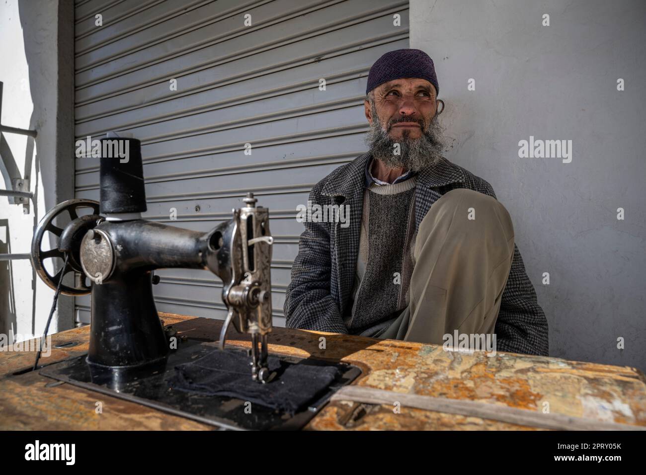 Tailor repairing clothes with his sewing machine in a street stall ...
