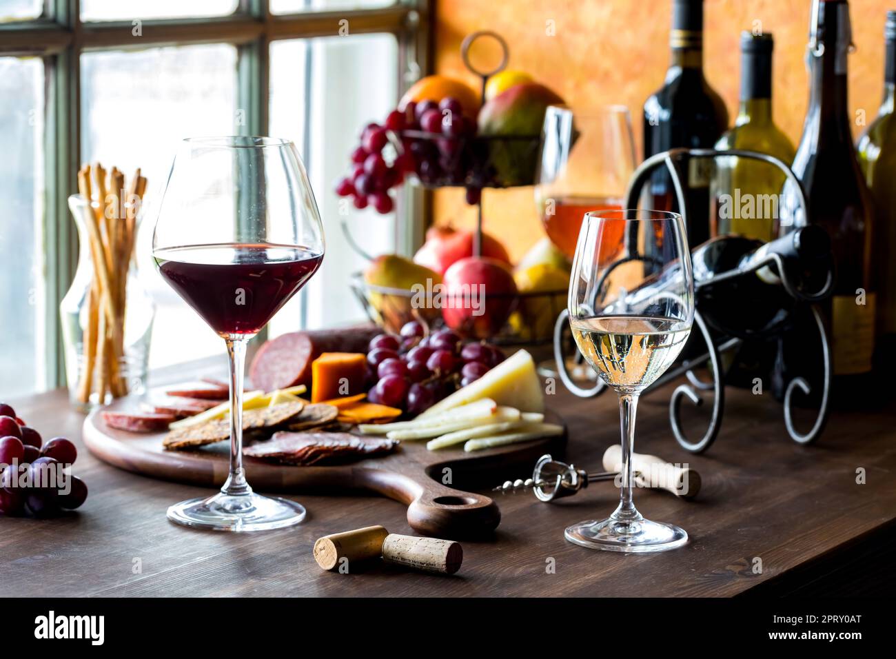 A rustic table top arrangement of various wine with a charcuterie board ...