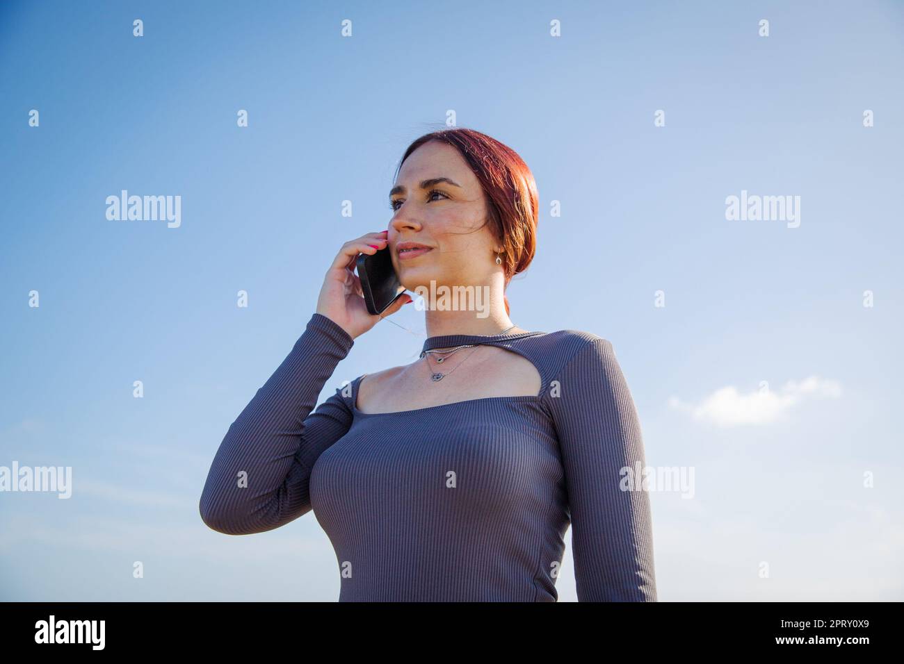 A young woman makes a phone call with the clear sky as background Stock ...