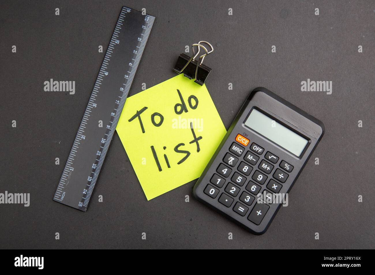 top view to do list written on sticky note ruler calculator on dark ...
