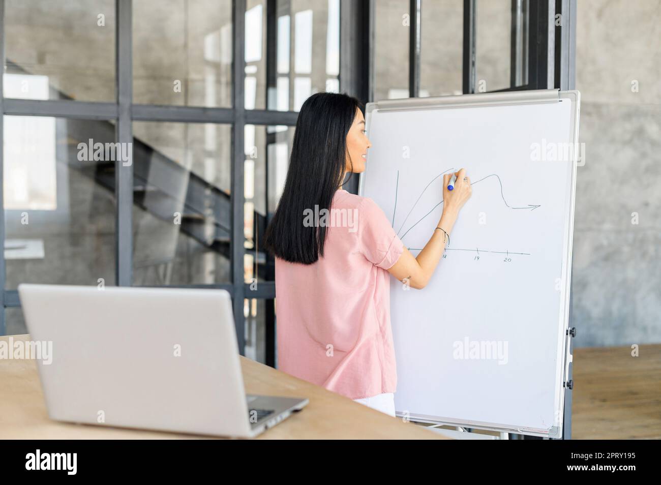 Rear view of a girl drawing graph or diagram on an interactive ...