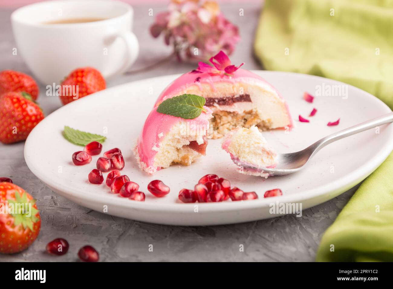 Pink mousse cake with strawberry and a cup of coffee on a gray concrete ...