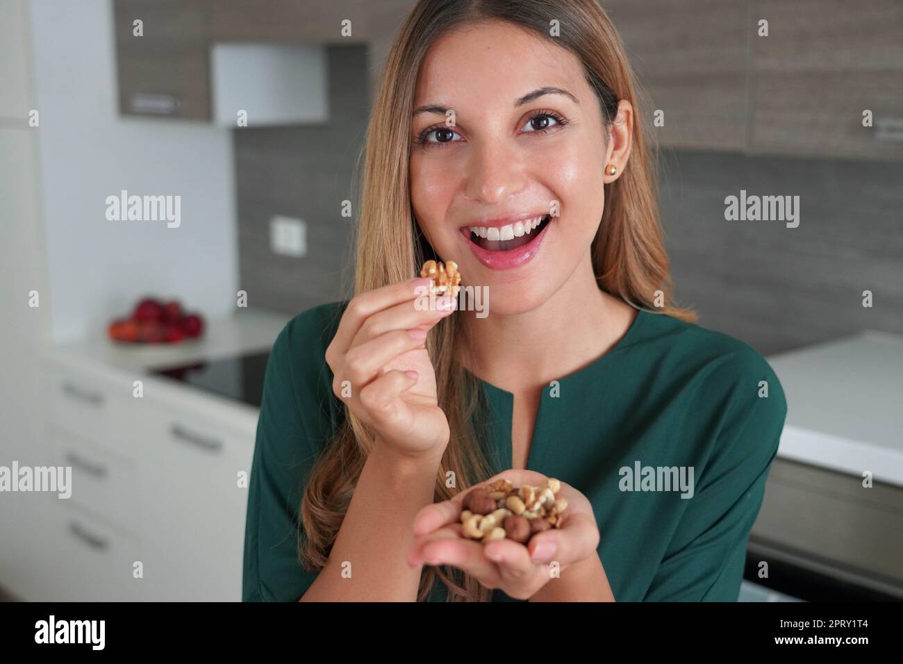 Beautiful healthy woman eating mix of nuts seeds dried fruit indoor ...