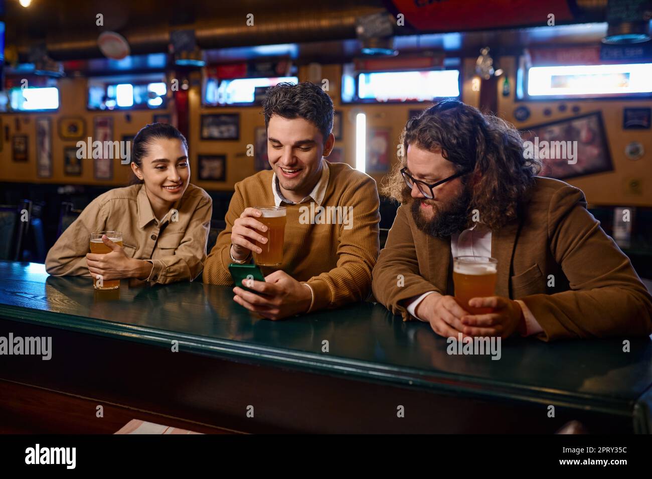 Friends having fun sitting at bar counter in pub. Young people talking ...