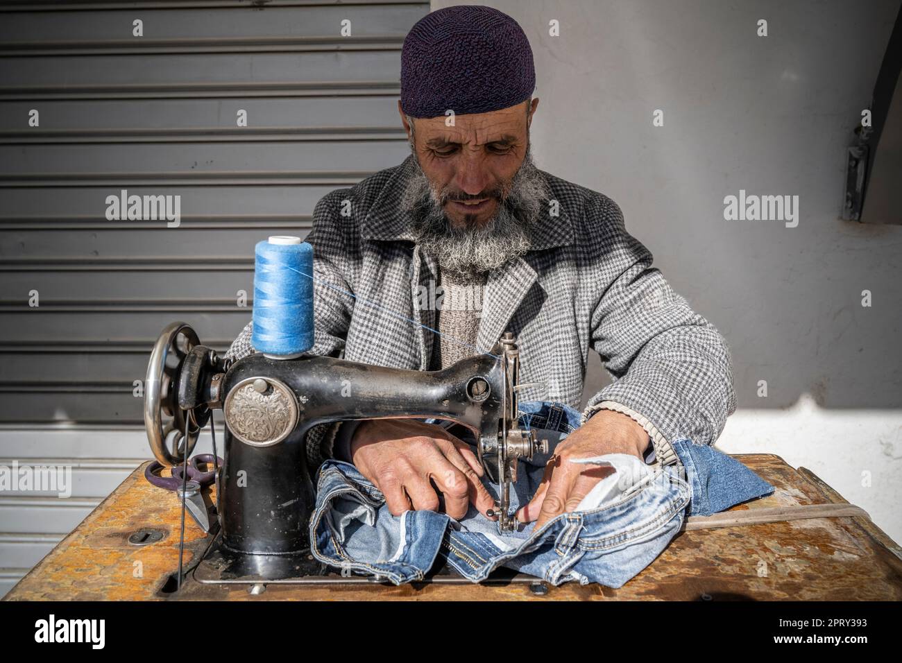 Tailor repairing clothes with his sewing machine in a street stall ...