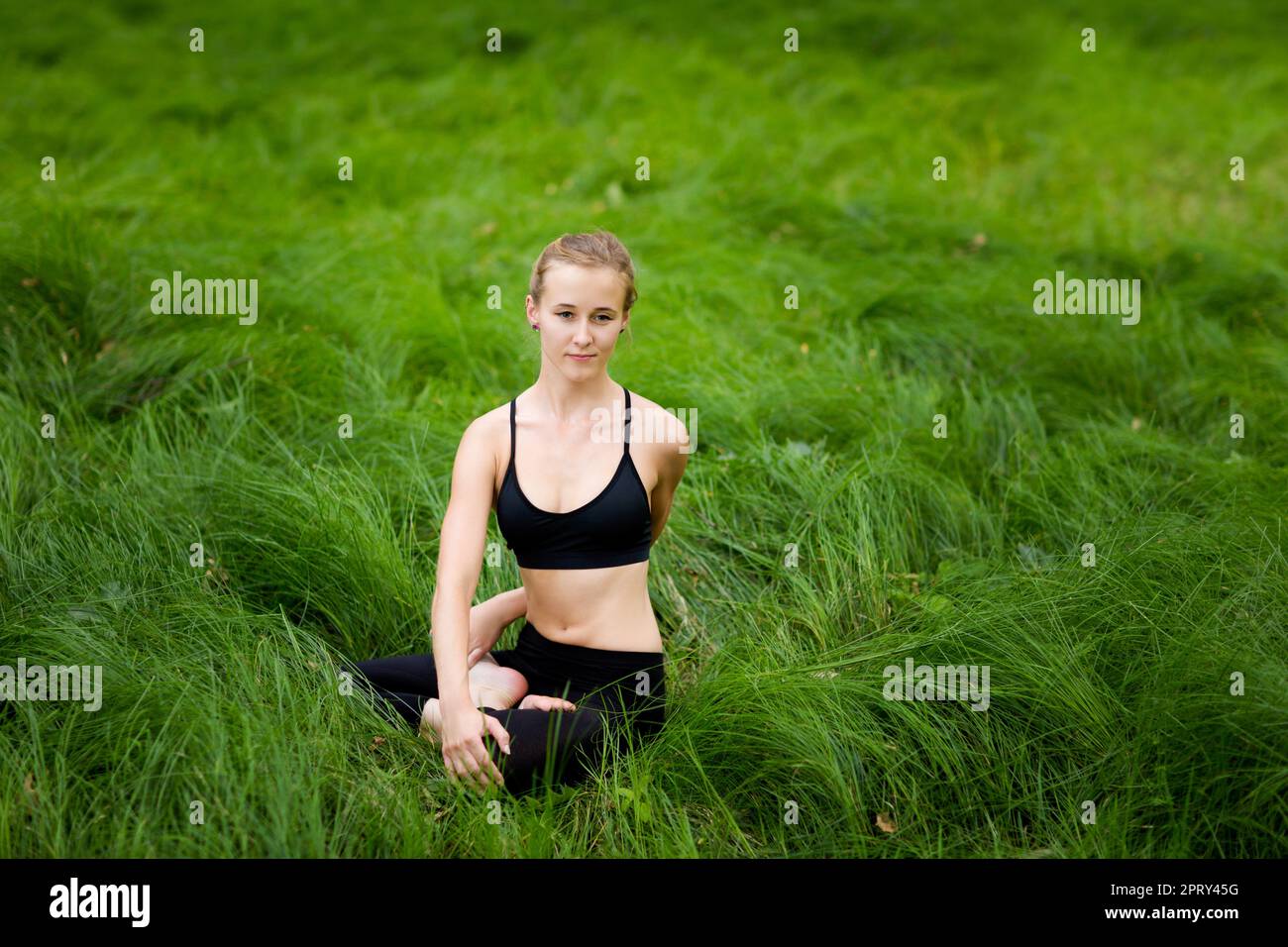 Nature yoga session in beautiful green polish woods, between trees. Meditation -twisted lotus ...
