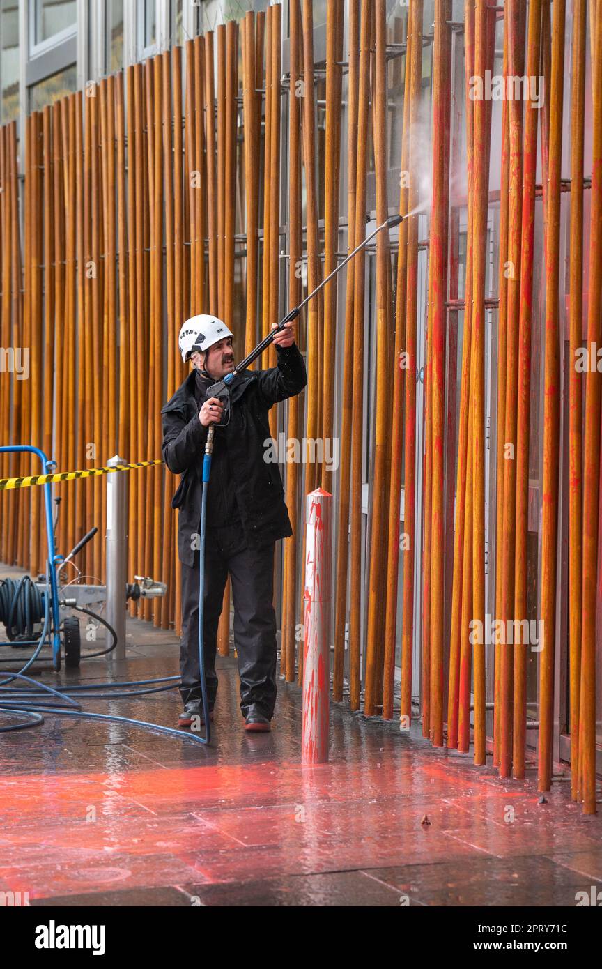 Workmen clean up red paint that was thrown by climate activists outside ...