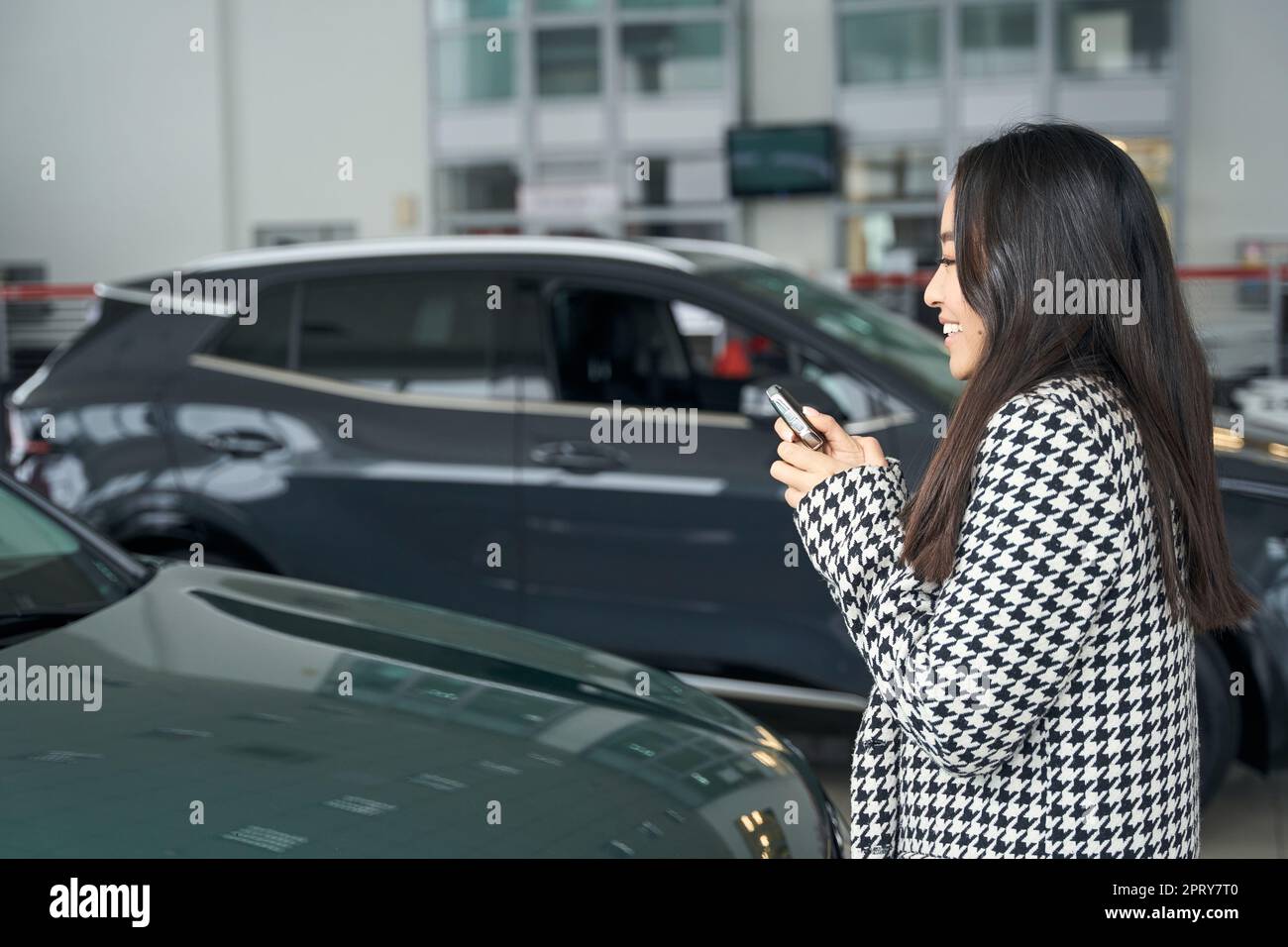 Asian female stands in a car dealership with car keys Stock Photo - Alamy