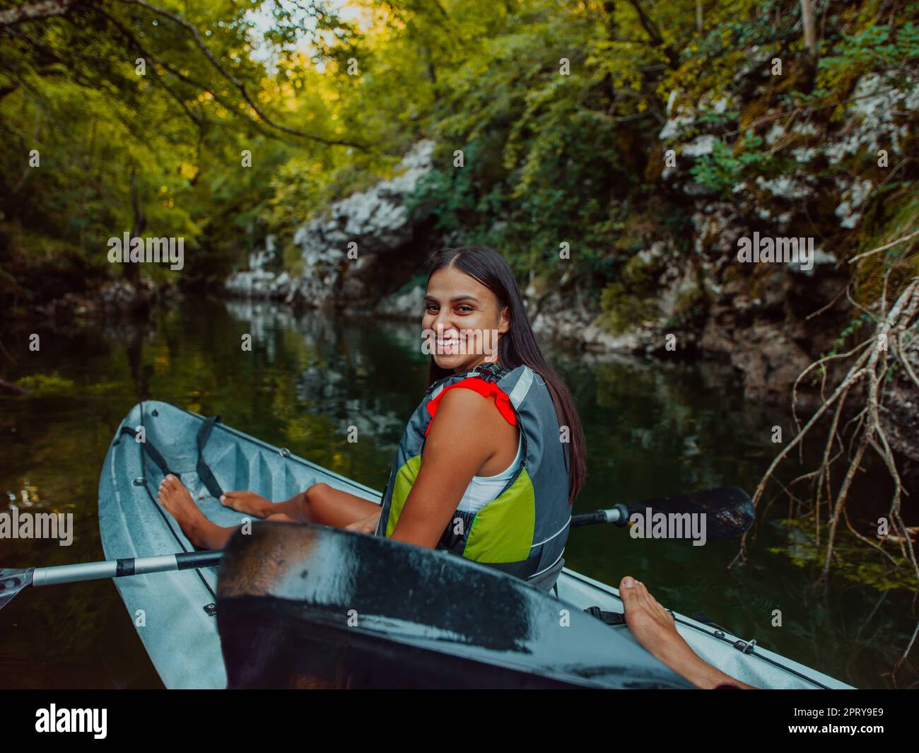A smiling woman enjoying a relaxing kayak ride with a friend while ...