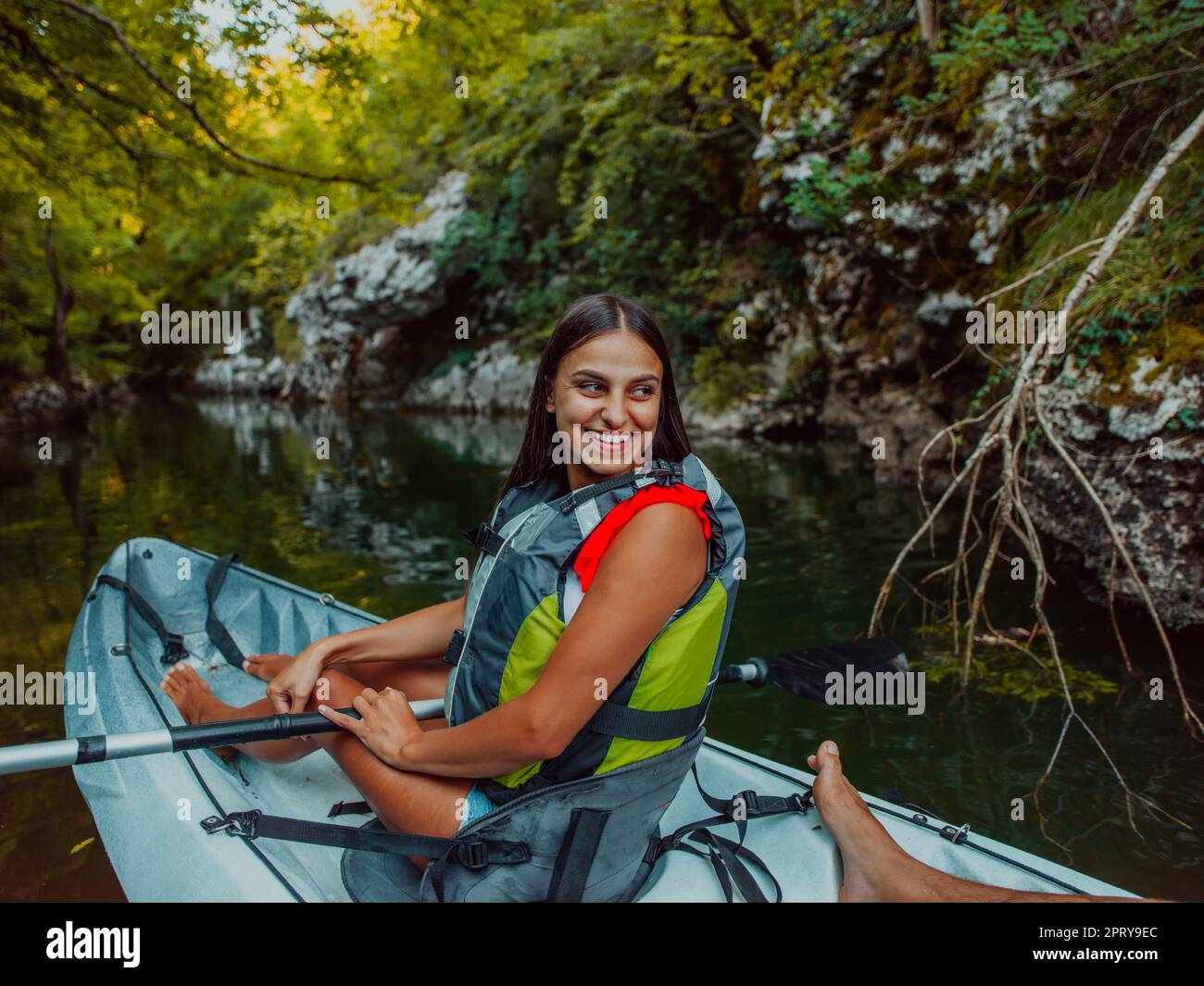 A smiling woman enjoying a relaxing kayak ride with a friend while ...