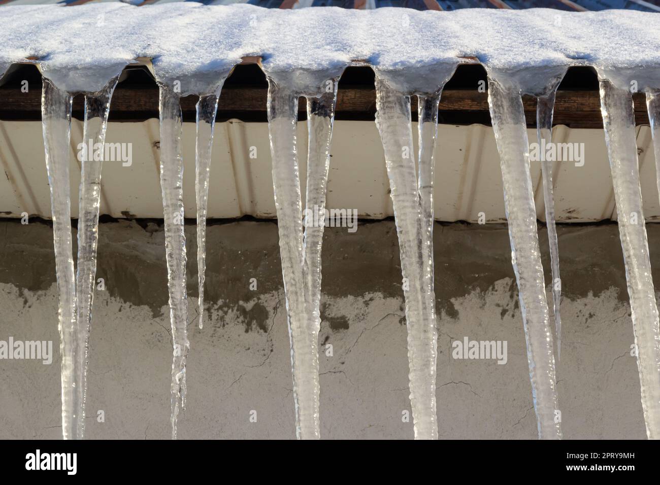 Sharp icicles and melted snow hanging from eaves of roof. Beautiful ...