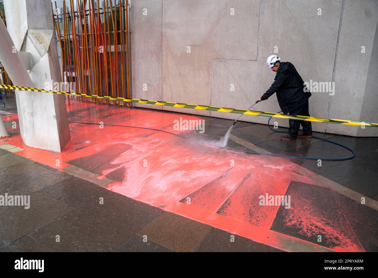 Workmen clean up red paint that was thrown by climate activists outside ...