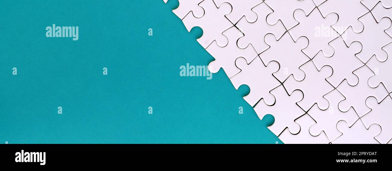 Fragment of a folded white jigsaw puzzle on the background of a blue ...