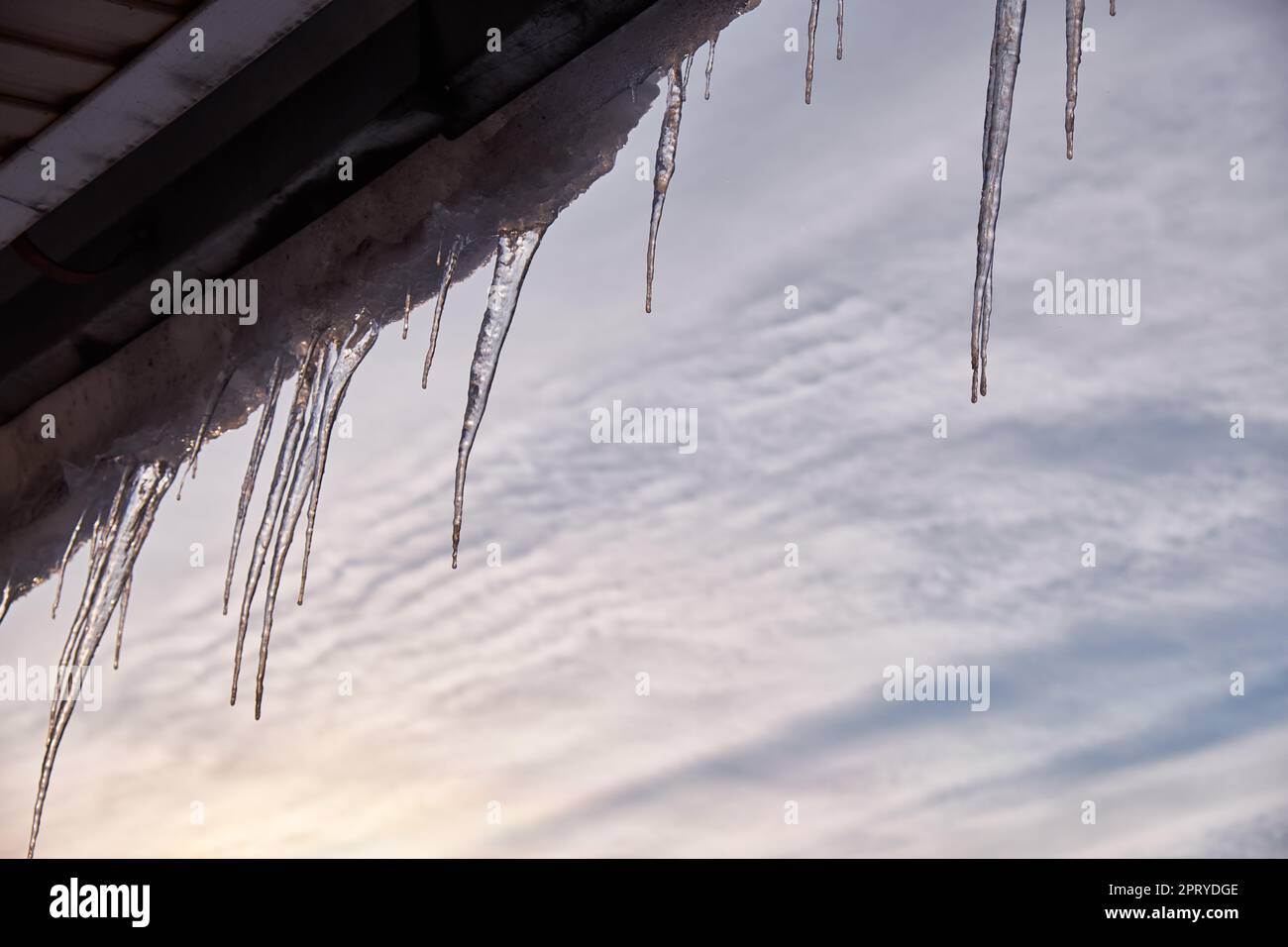 Dropping icicles on a warm spring day hang from the wooden roof of an ...