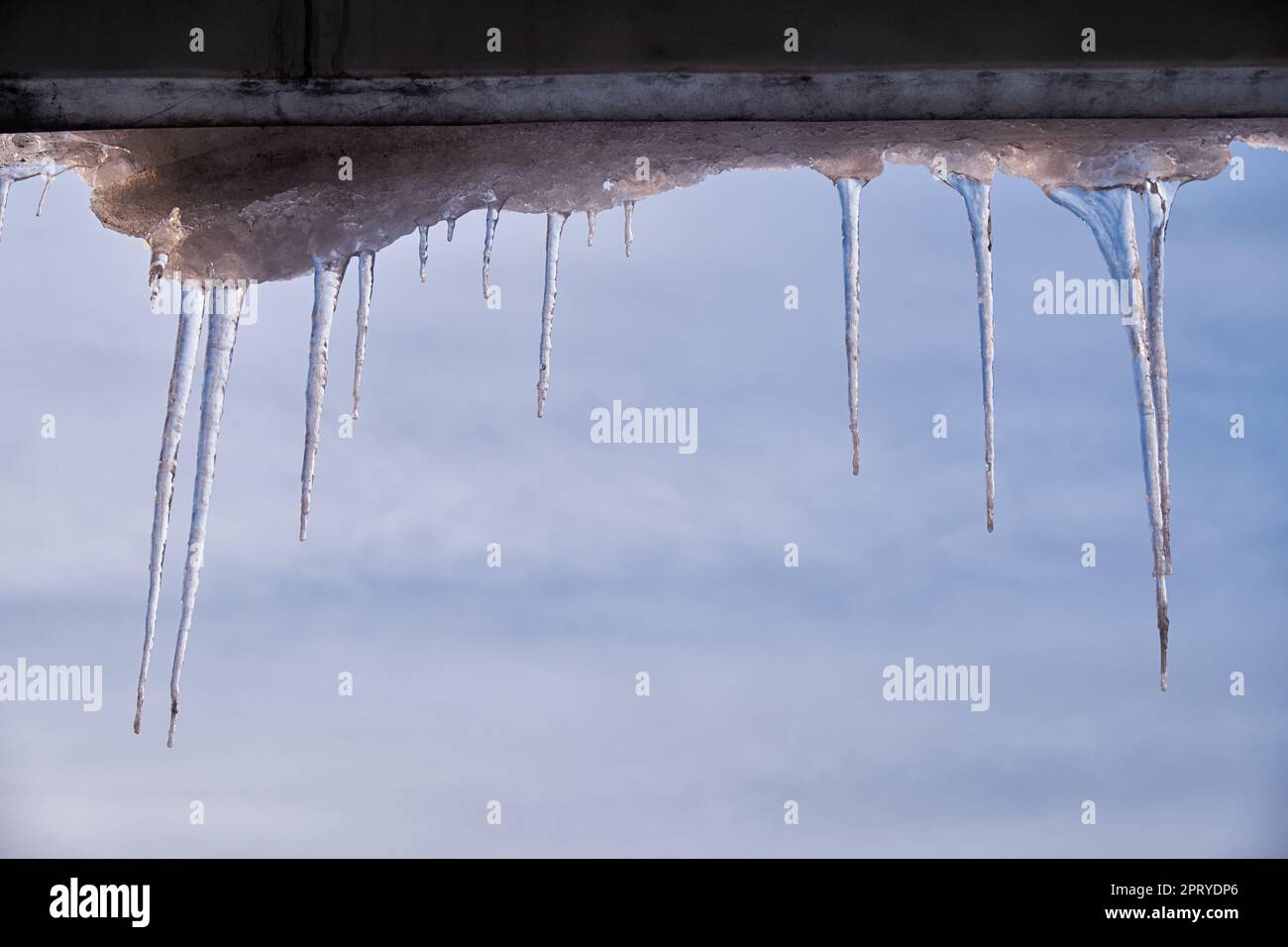 Dropping icicles on a warm spring day hang from the wooden roof of an ...