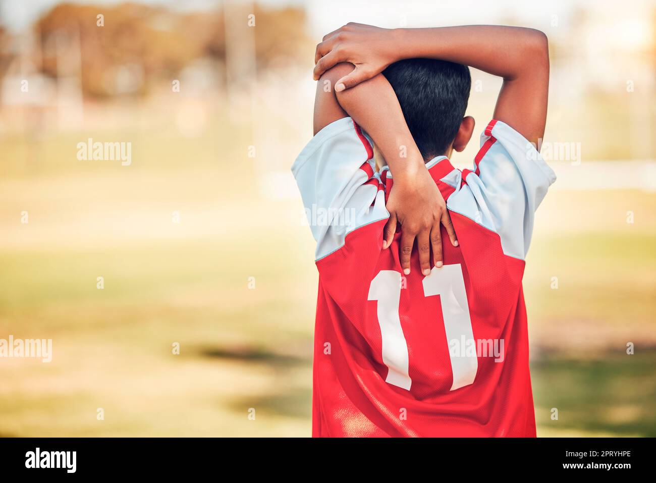 Soccer, football and boy stretching arm getting ready for training ...