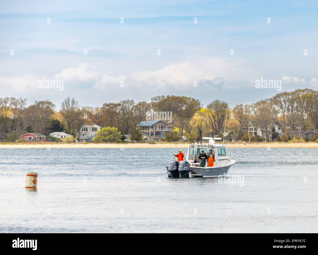 Three men fishing off the back of a boat off the coast of shelter ...