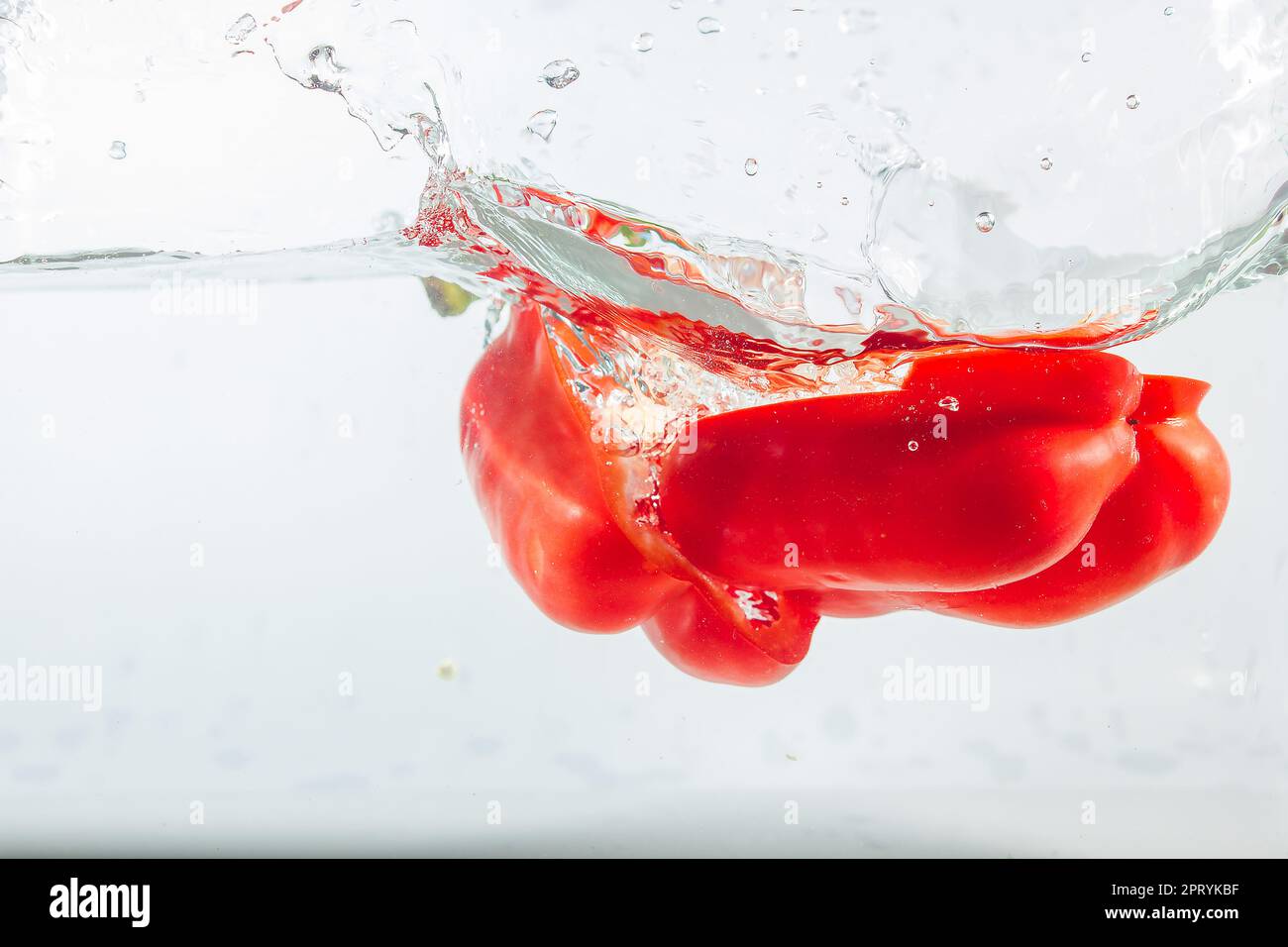 Sweet pepper in water splashes, red sweet pepper on a white background ...