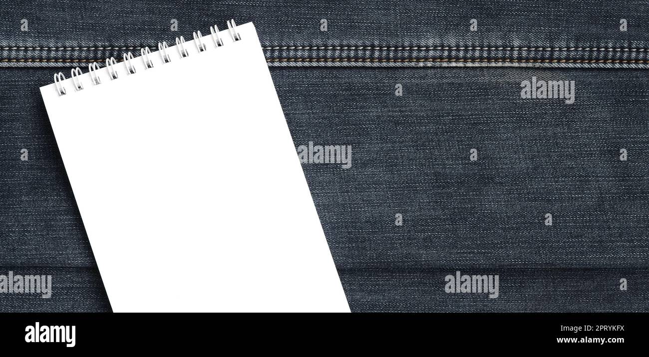 White notebook with clean pages lying on dark blue jeans background ...
