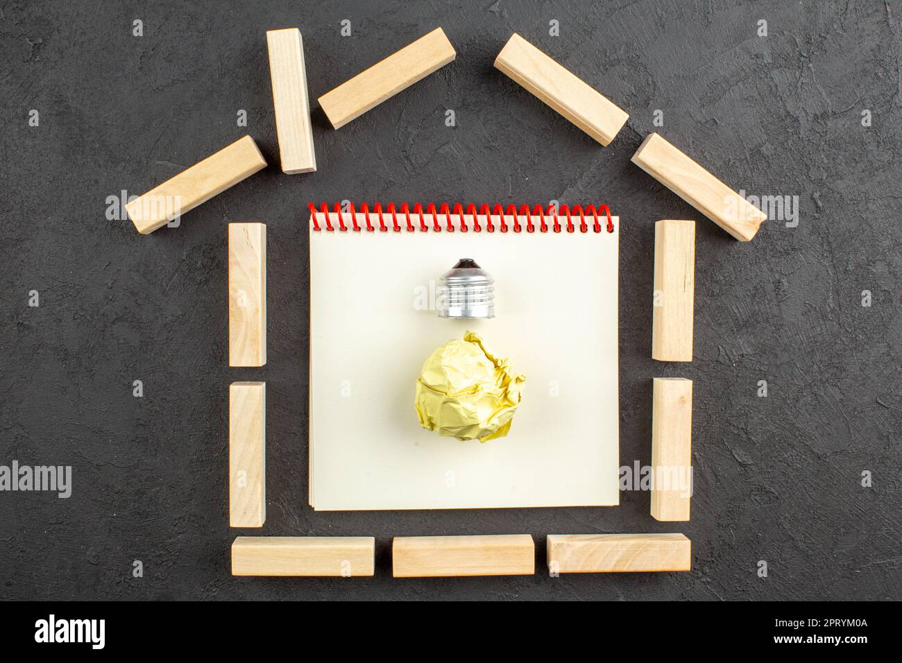top view house shaped wood blocks idealight bulb on notepad on black ...