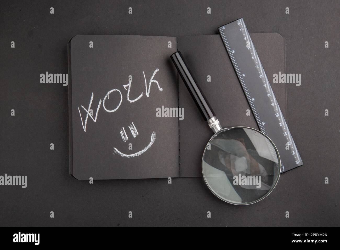 top view work written on black notebook lupa ruler on dark background ...