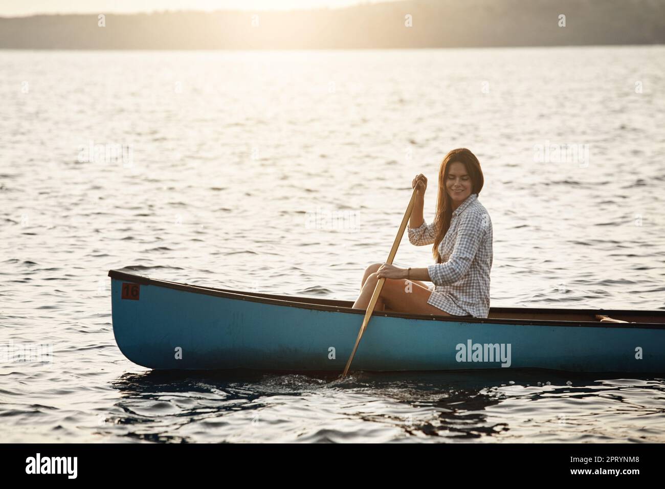 Rowing herself all the way to adventure. a beautiful young woman rowing ...