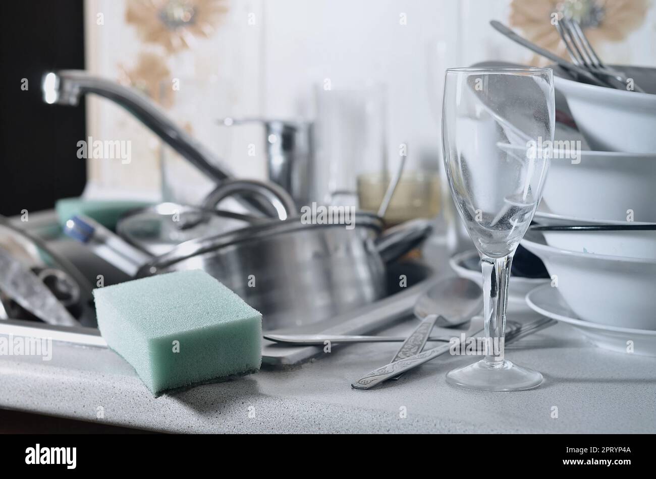 A huge pile of unwashed dishes in the kitchen sink and on the ...