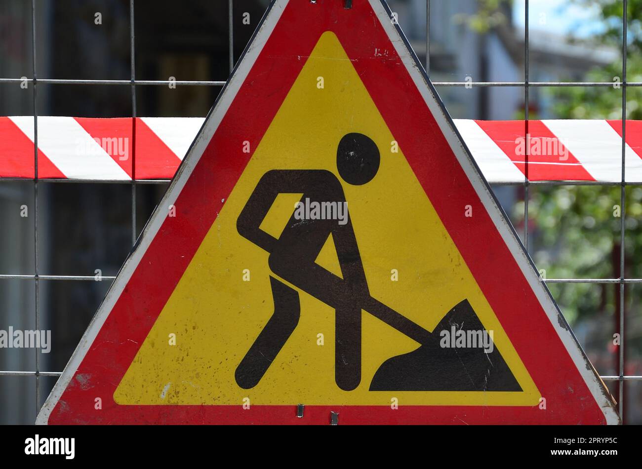 The warning sign "under construction" is attached to a metal mesh fence ...